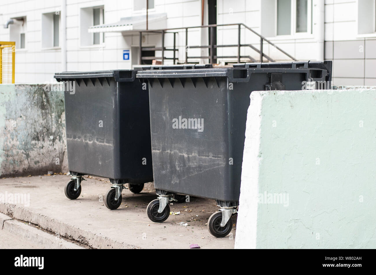 Garbage bins near housing block. Dumpsters on the grey wall background ...