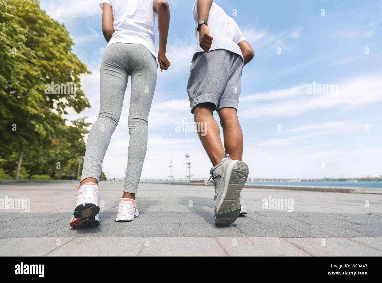Unrecognizable Black Couple Jogging Along River Bank, Low-Angle, Rear ...