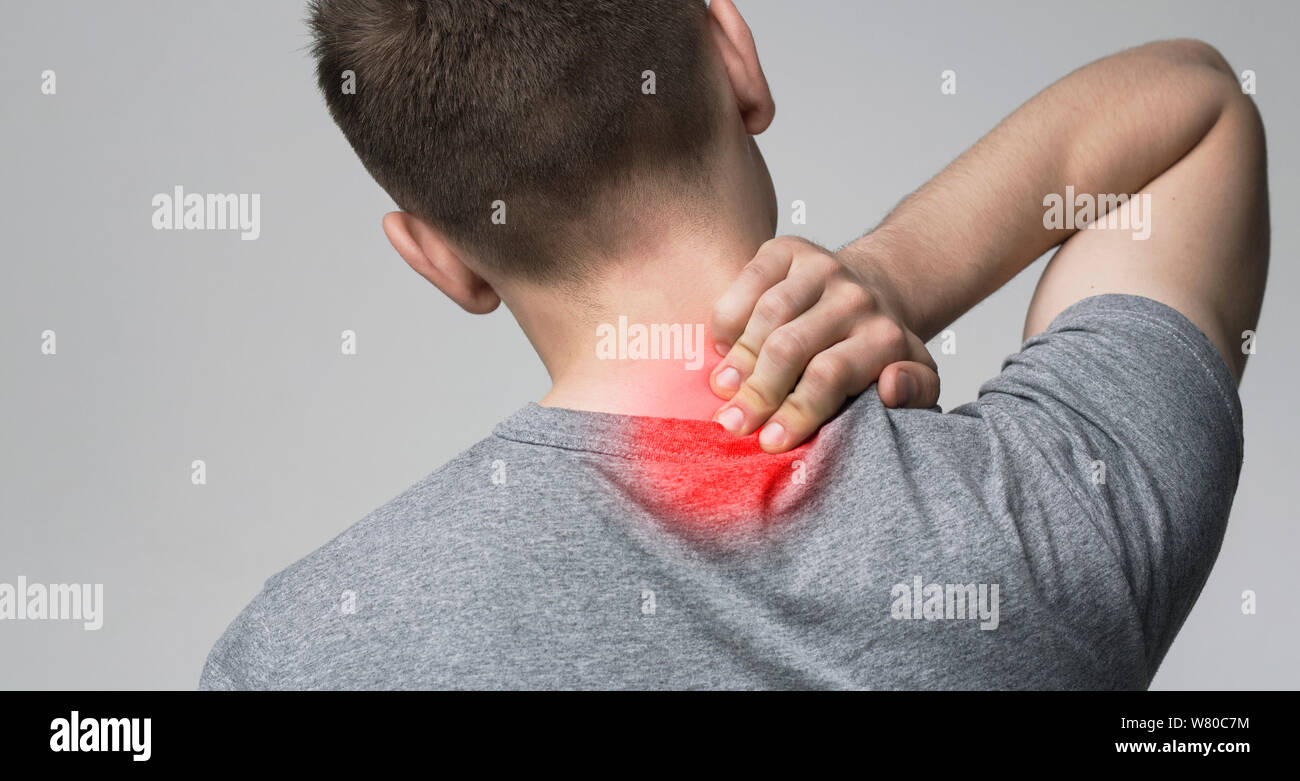 Young man massaging his sore neck, back view Stock Photo - Alamy