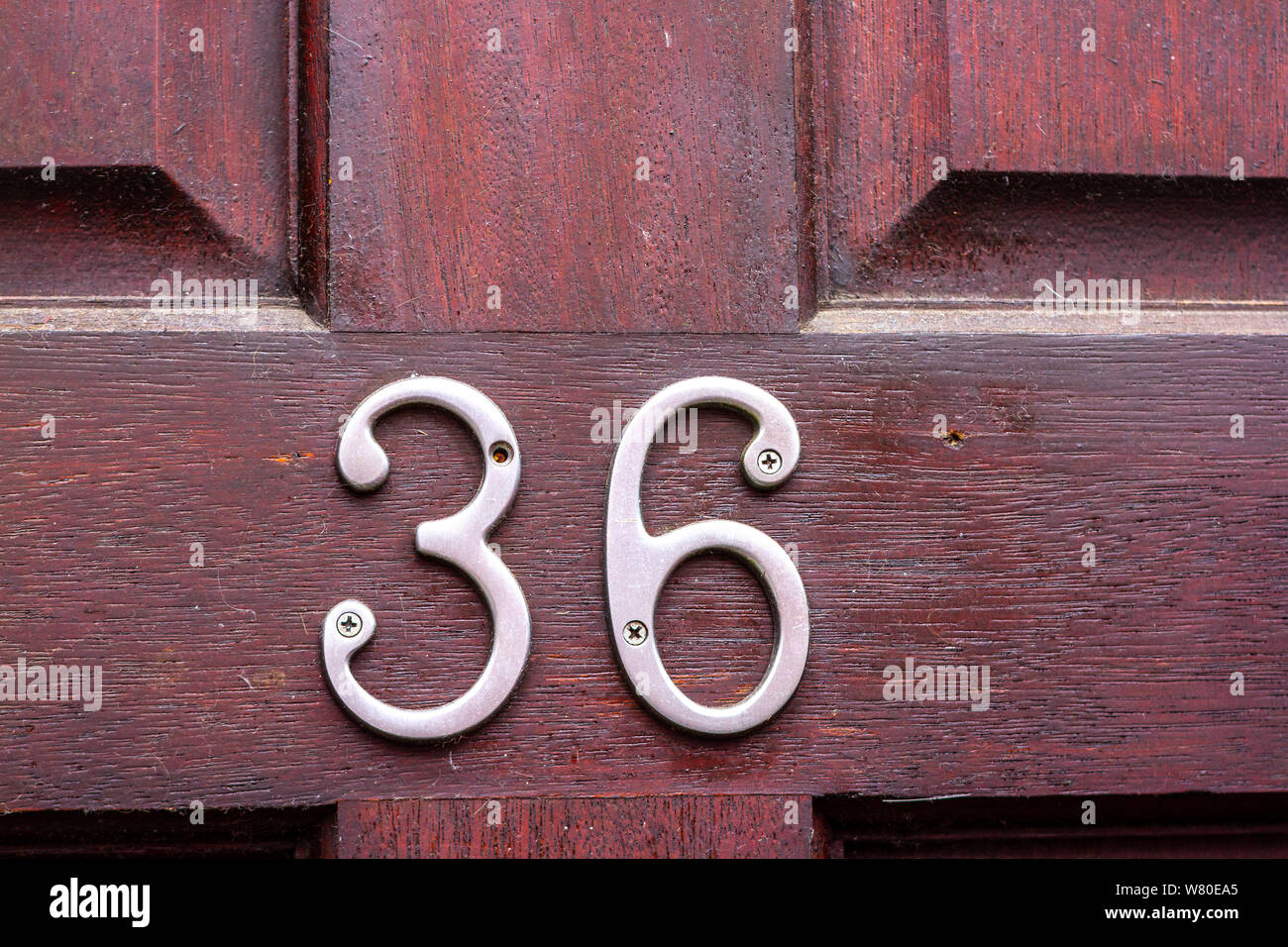 House number 36 in silver metal digits on a red wooden door made out of ...