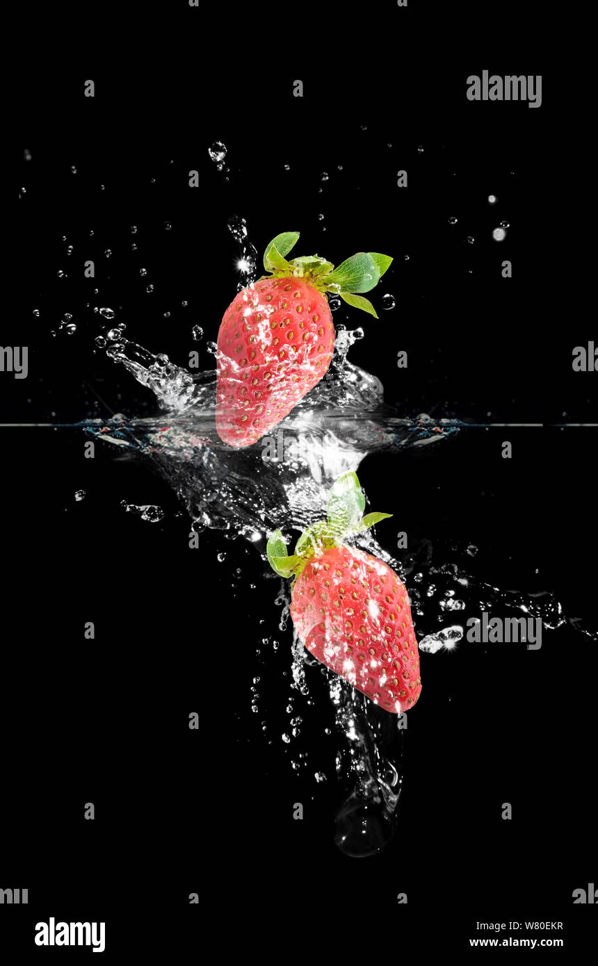 Strawberries splash on black background Stock Photo - Alamy