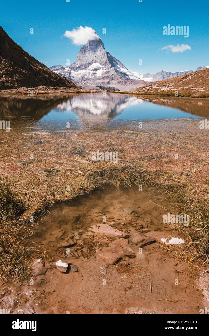 Body of water near rocky mountain during daytime with reflections and beautiful sky Stock Photo ...