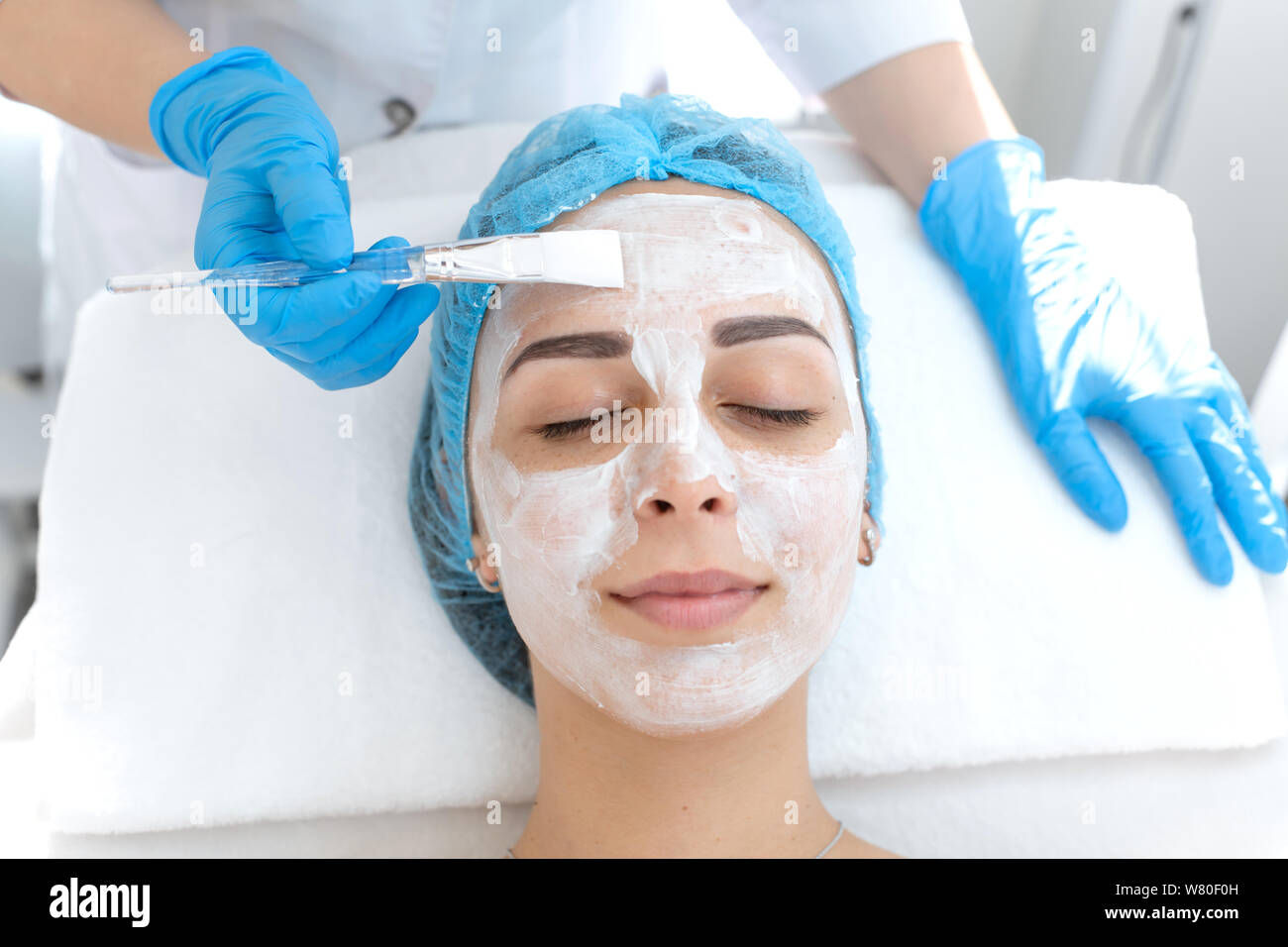 A professional cosmetologist applies a nourishing cream on the patient ...