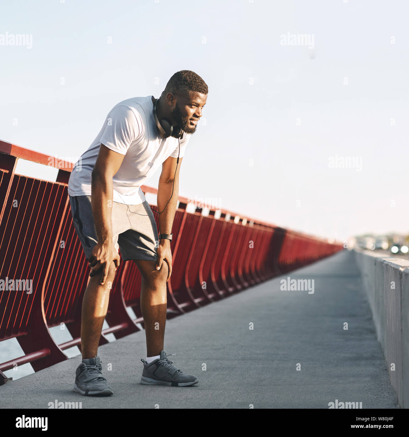Tired black sportsman holding hands on knees, resting Stock Photo - Alamy