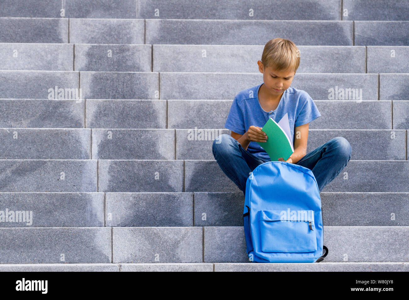 Boy reading book sitting on the stairs outdoors Stock Photo - Alamy