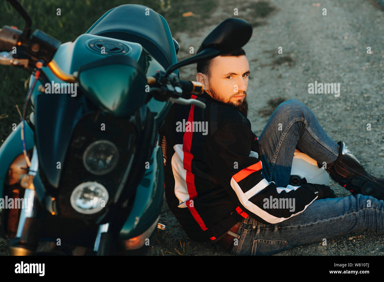 Portrait of a bearded confident man sitting in the ground leaning on ...