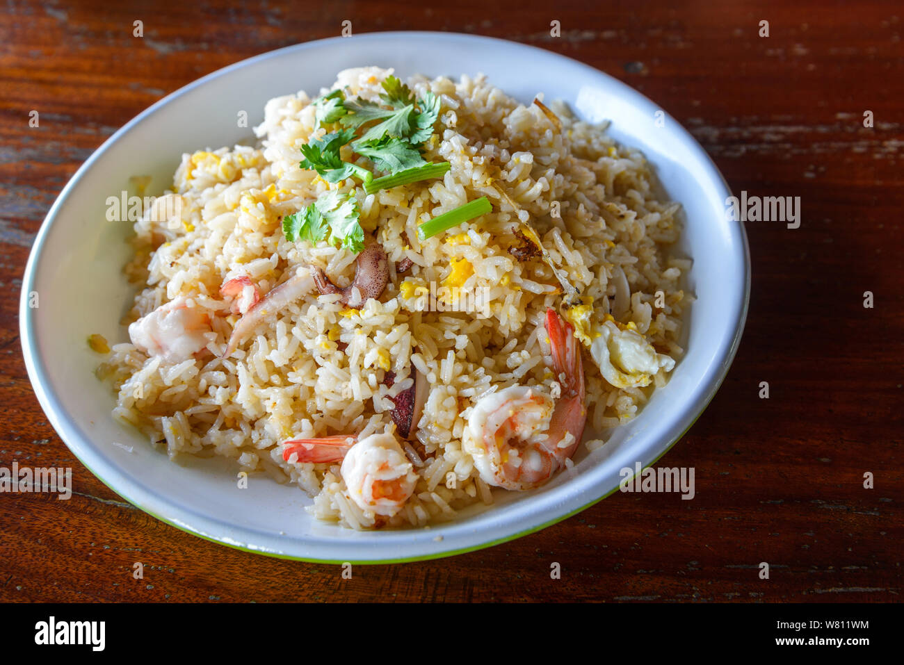 Thai Asian seafood fried rice with shrimp and squid on white dish and ...