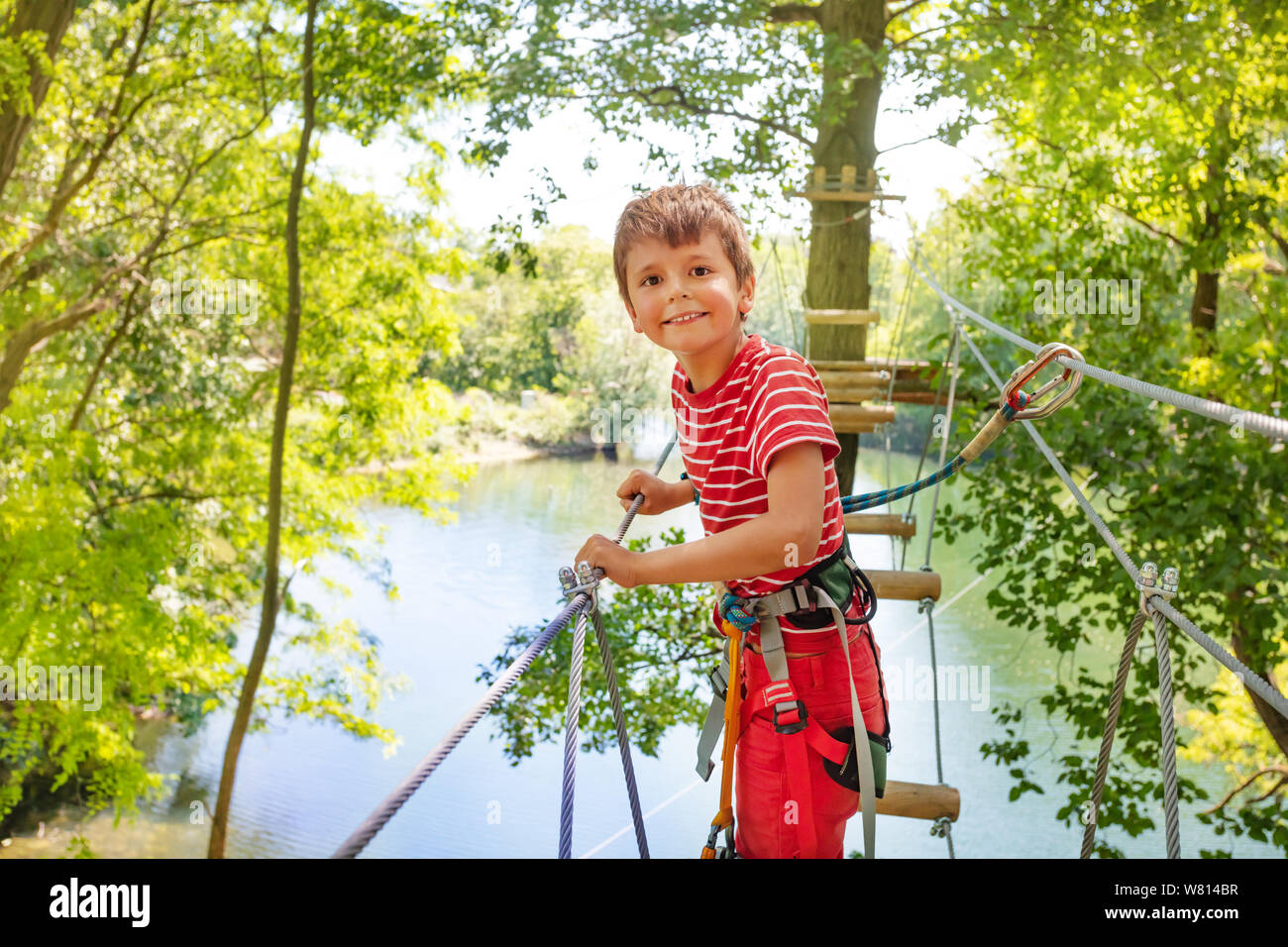 Happy boy on tree rope bridge in adventure park Stock Photo - Alamy