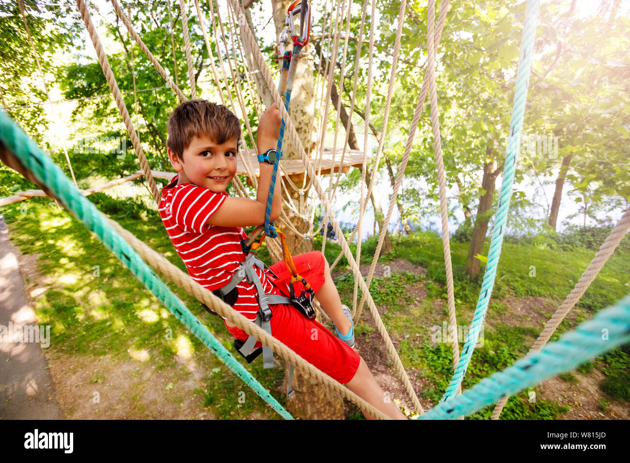 Happy boy pass ropes exercise at adventure park Stock Photo - Alamy