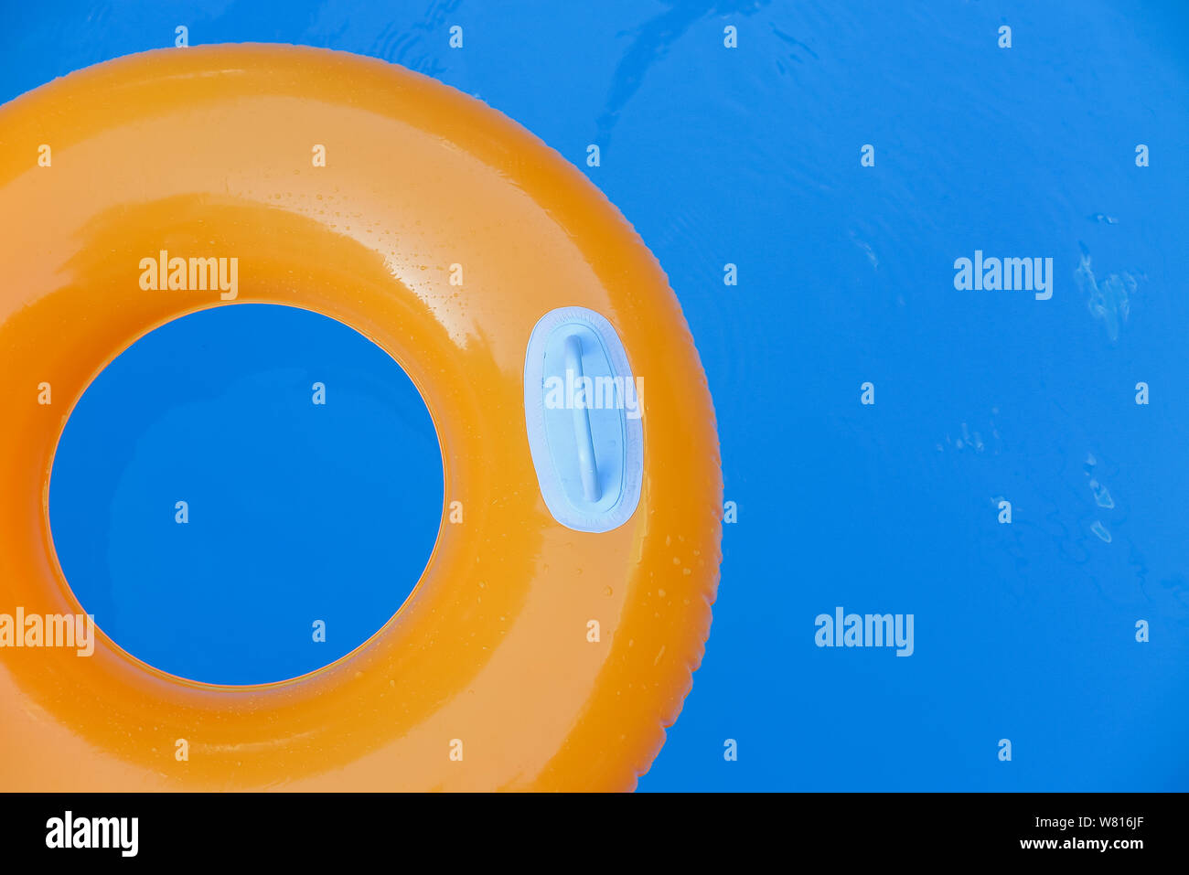 Children inflatable orange swimming ring with white handles floating in ...