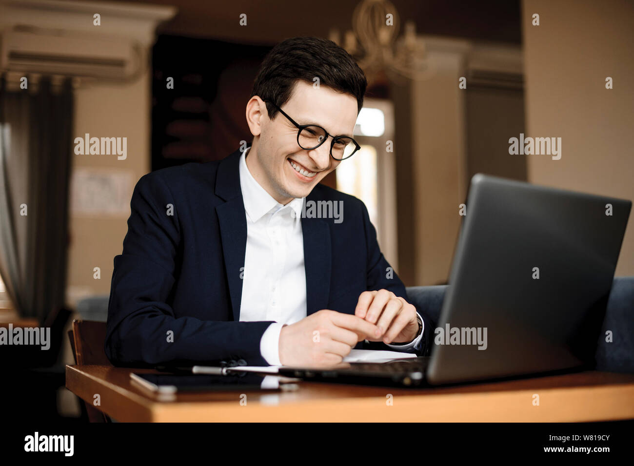 Portrait of handsome caucasian manager sitting at his desk laughing ...