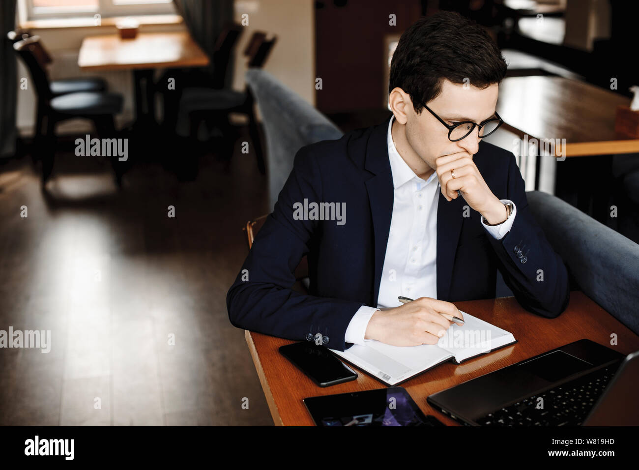 Portrait of a young confident business man working while sitting a ta ...