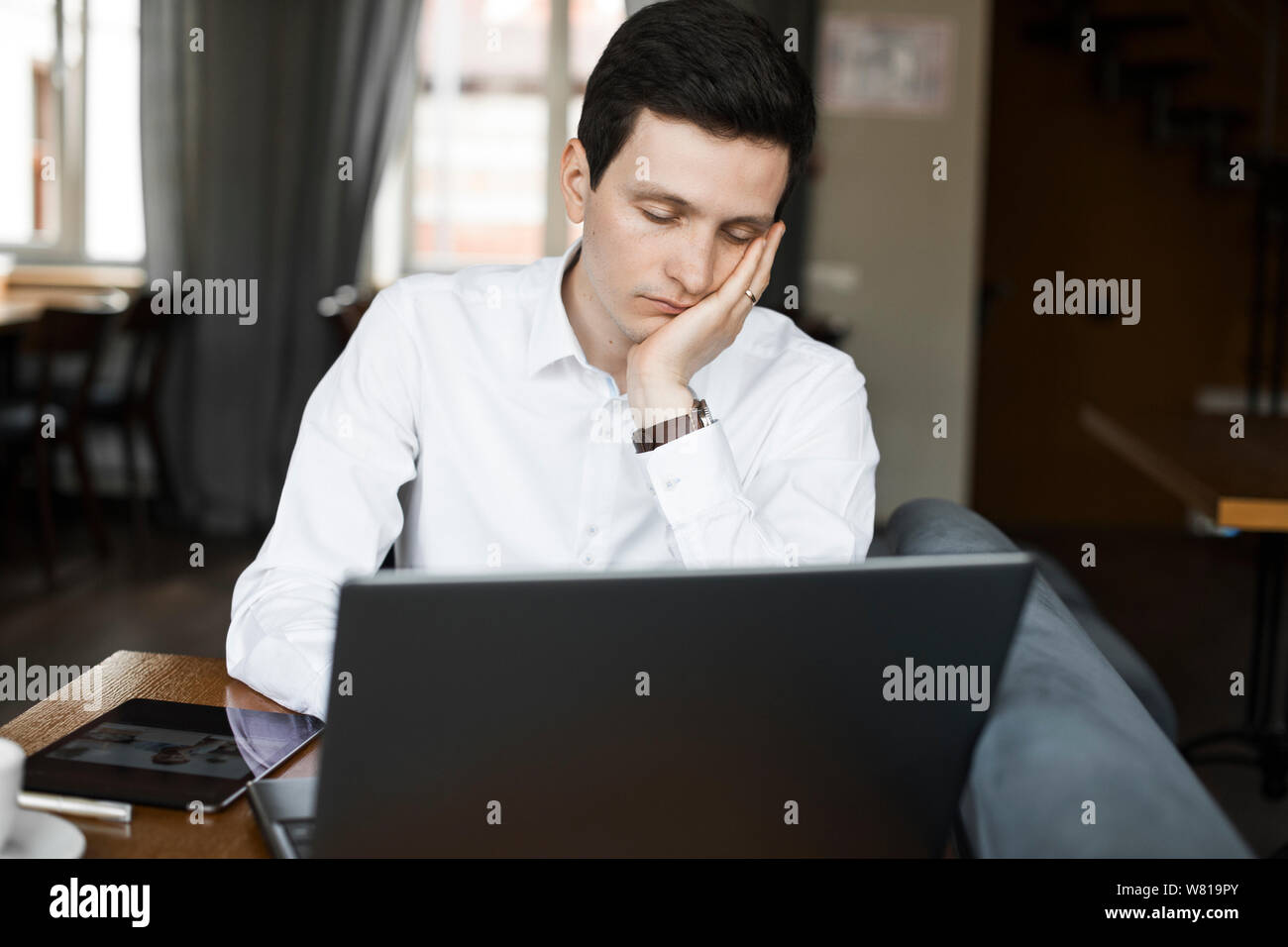 Portrait of tired elegant entrepreneur sitting in a coffee shop ...