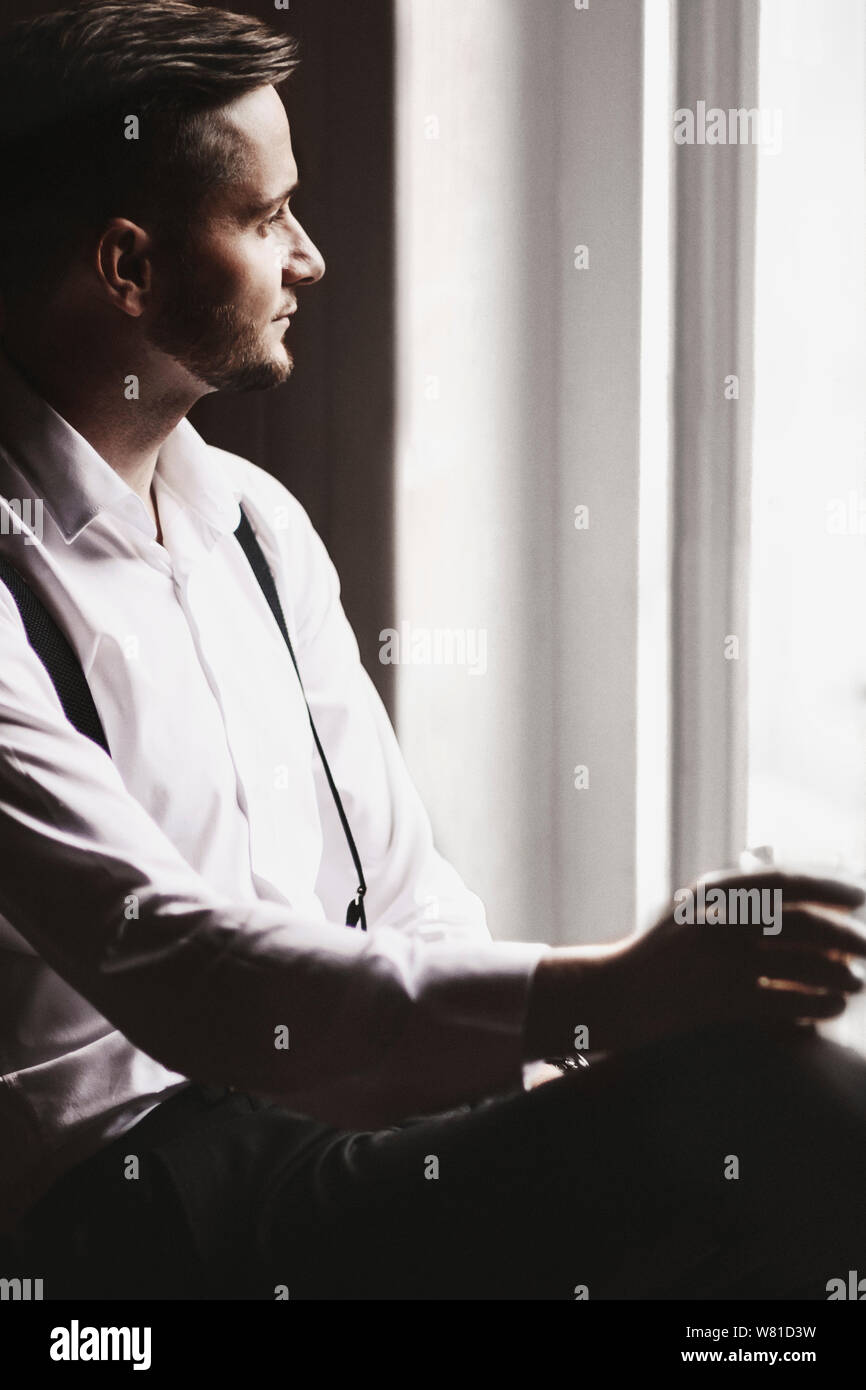 Side view portrait of a young caucasian groom drinking in the morning ...