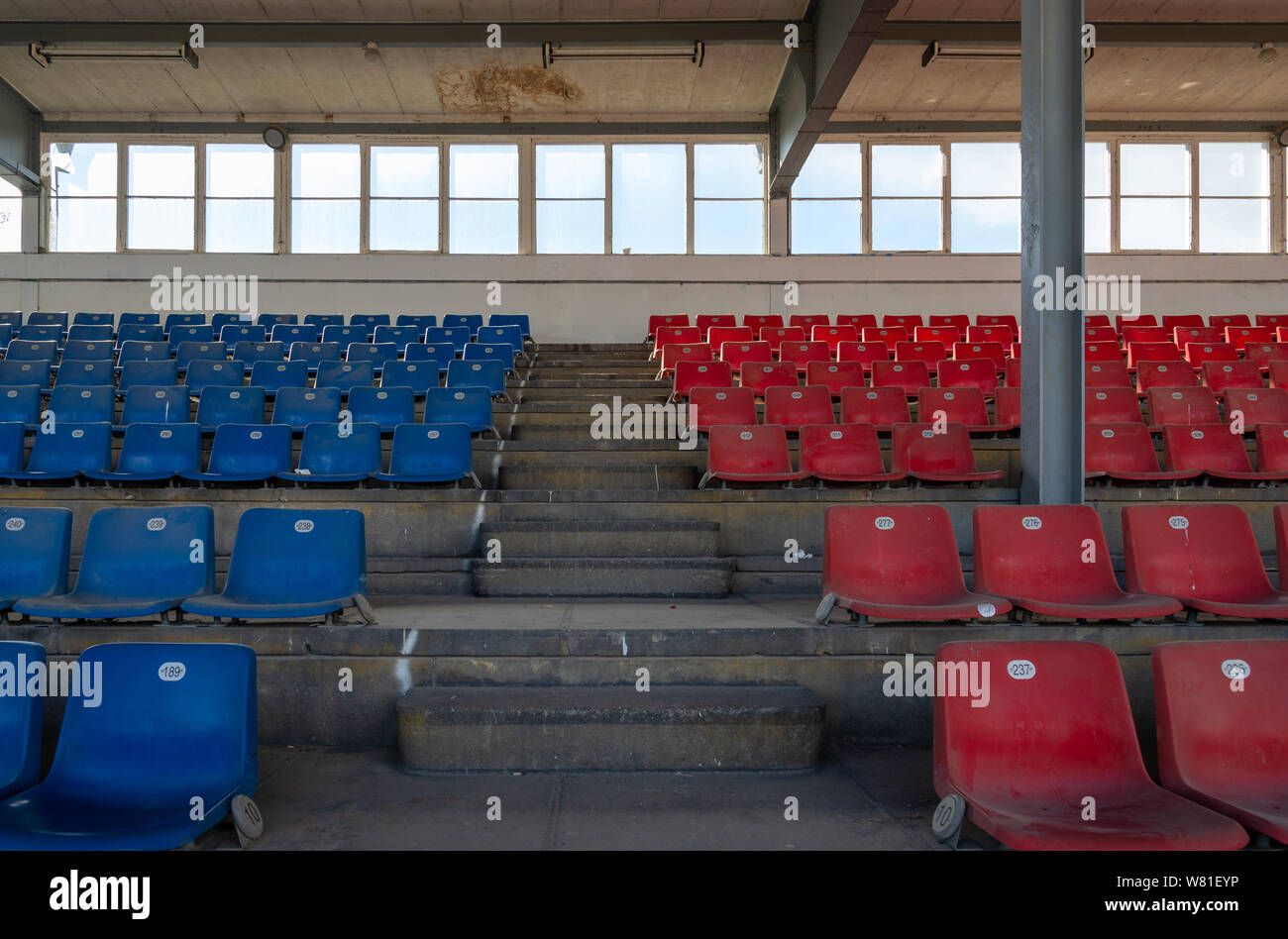 Front view row of blue and red plastic seats on rough concrete ...