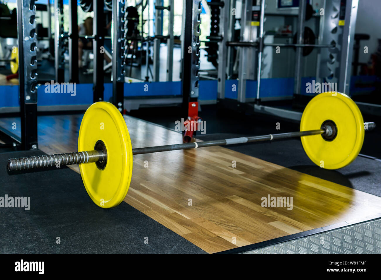 barbell with bright yellow plates in the gym in front of the weight ...