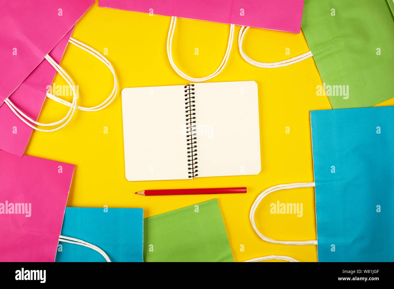 open notebook with blank white sheets and multi-colored paper shopping ...