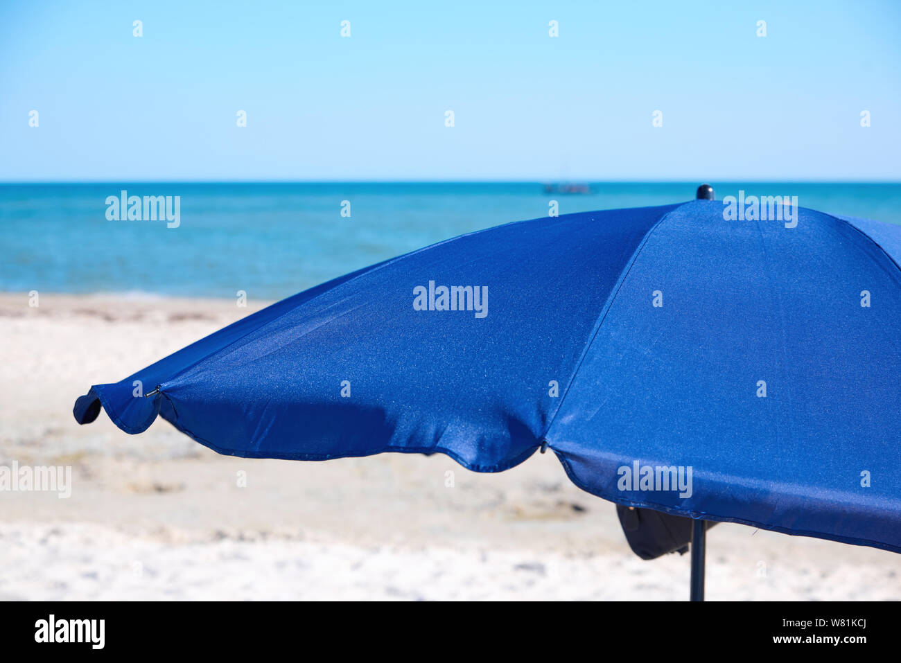 open blue textile beach umbrella on a sandy seashore, vacation concept ...