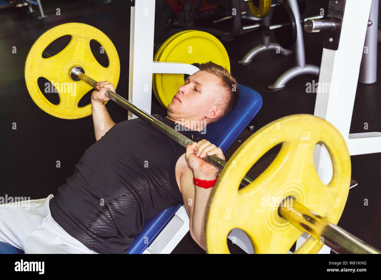 young man performs an exercise barbell bench press from the chest in ...