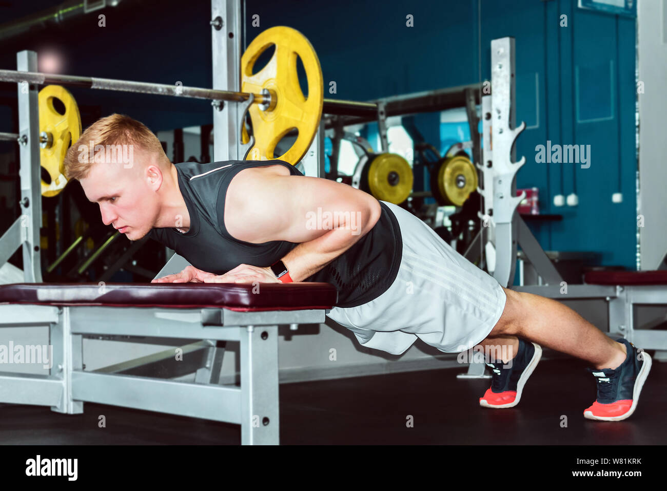 young man does push up exercise using a bench in the gym Stock Photo ...