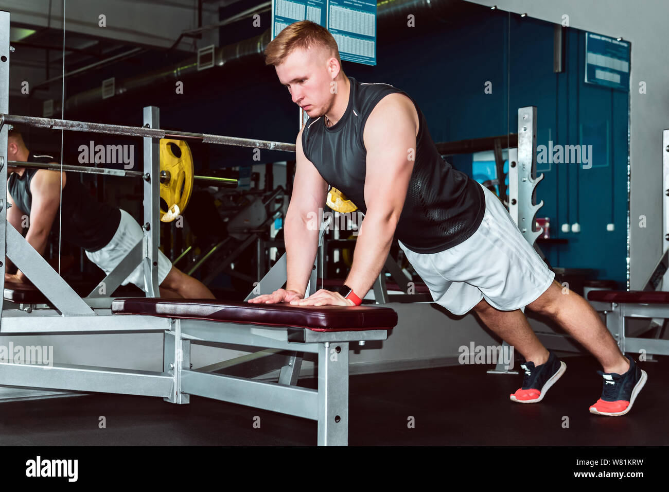 young man does push up exercise using a bench in the gym Stock Photo ...