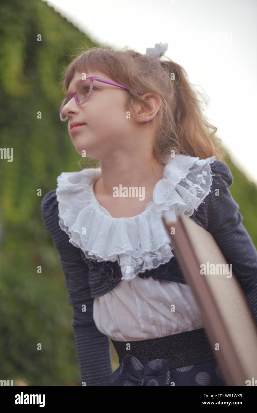 Schoolgirl with a big brown notebook on a background of greenery ...