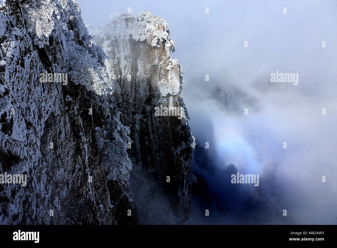 Landscape of pine trees covered with snow against a circular rainbow in the Huangshan Mountain ...