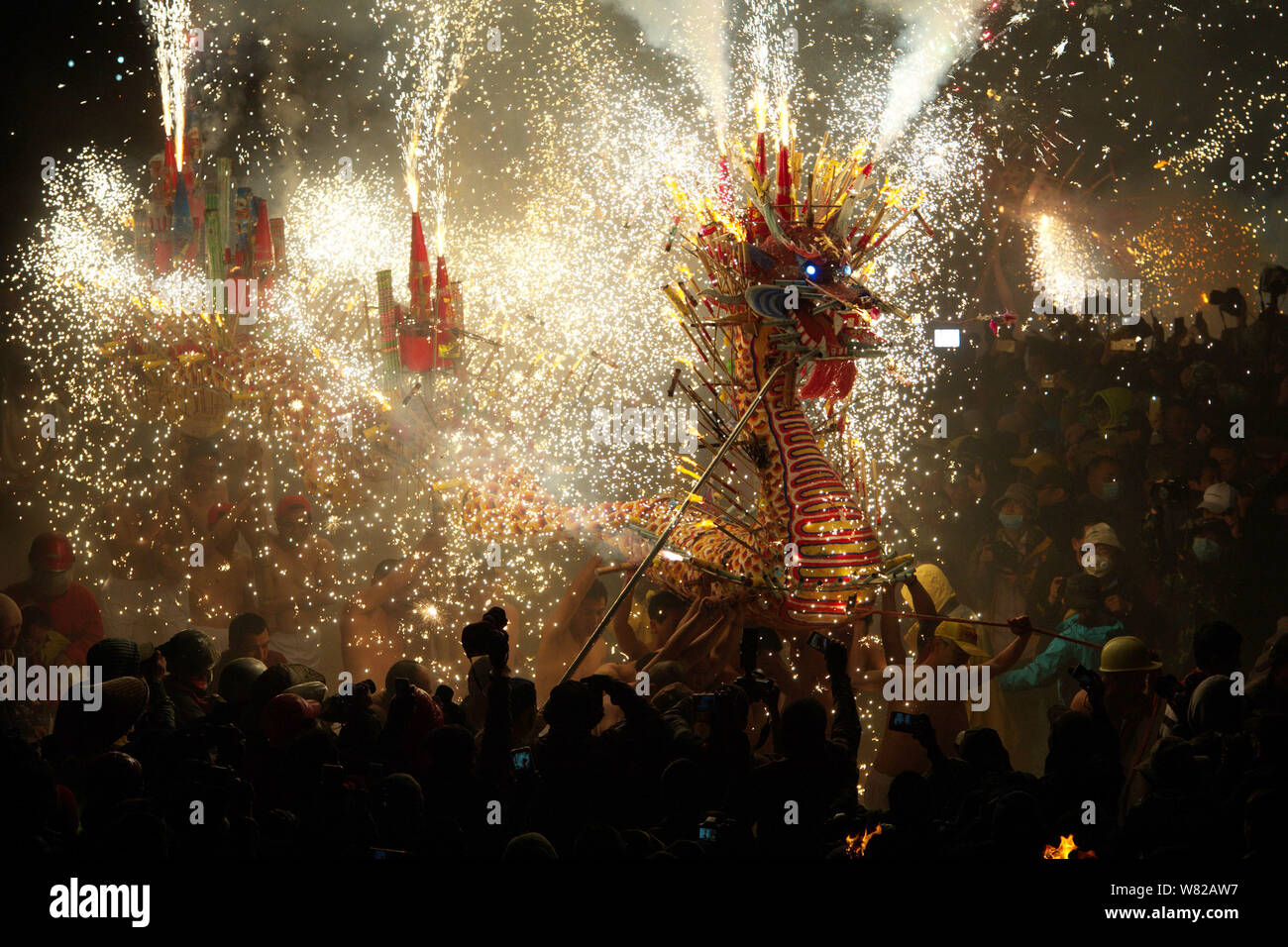 Chinese entertainers perform a dragon dance in sparks of fireworks to ...