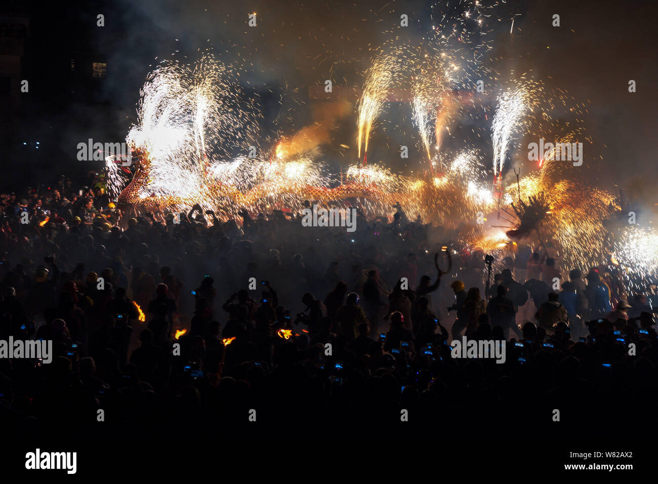 Chinese entertainers perform a dragon dance in sparks of fireworks to ...