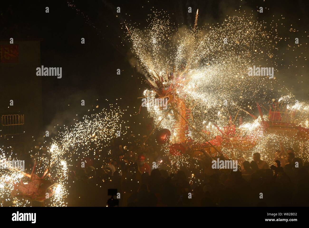 Chinese entertainers perform a dragon dance in sparks of fireworks to ...