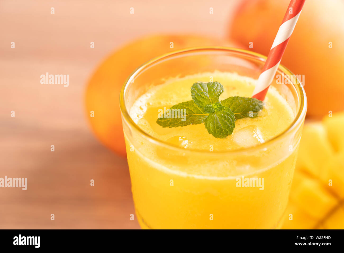 Fresh mango juice with beautiful chopped pulp flesh on bright wooden ...