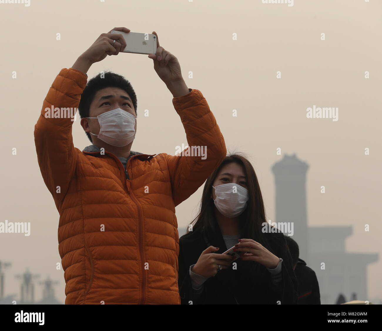 Tourists wearing face masks against air pollution take photos of Tian ...