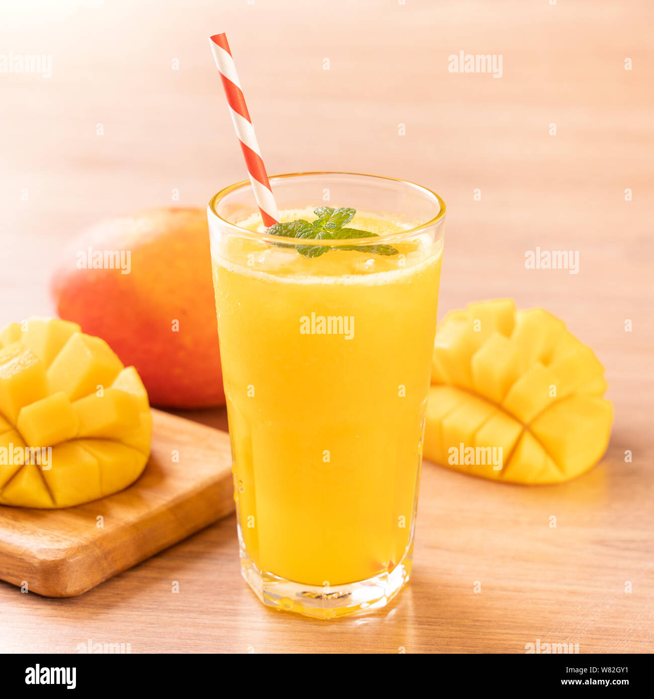 Fresh mango juice with beautiful chopped pulp flesh on bright wooden ...