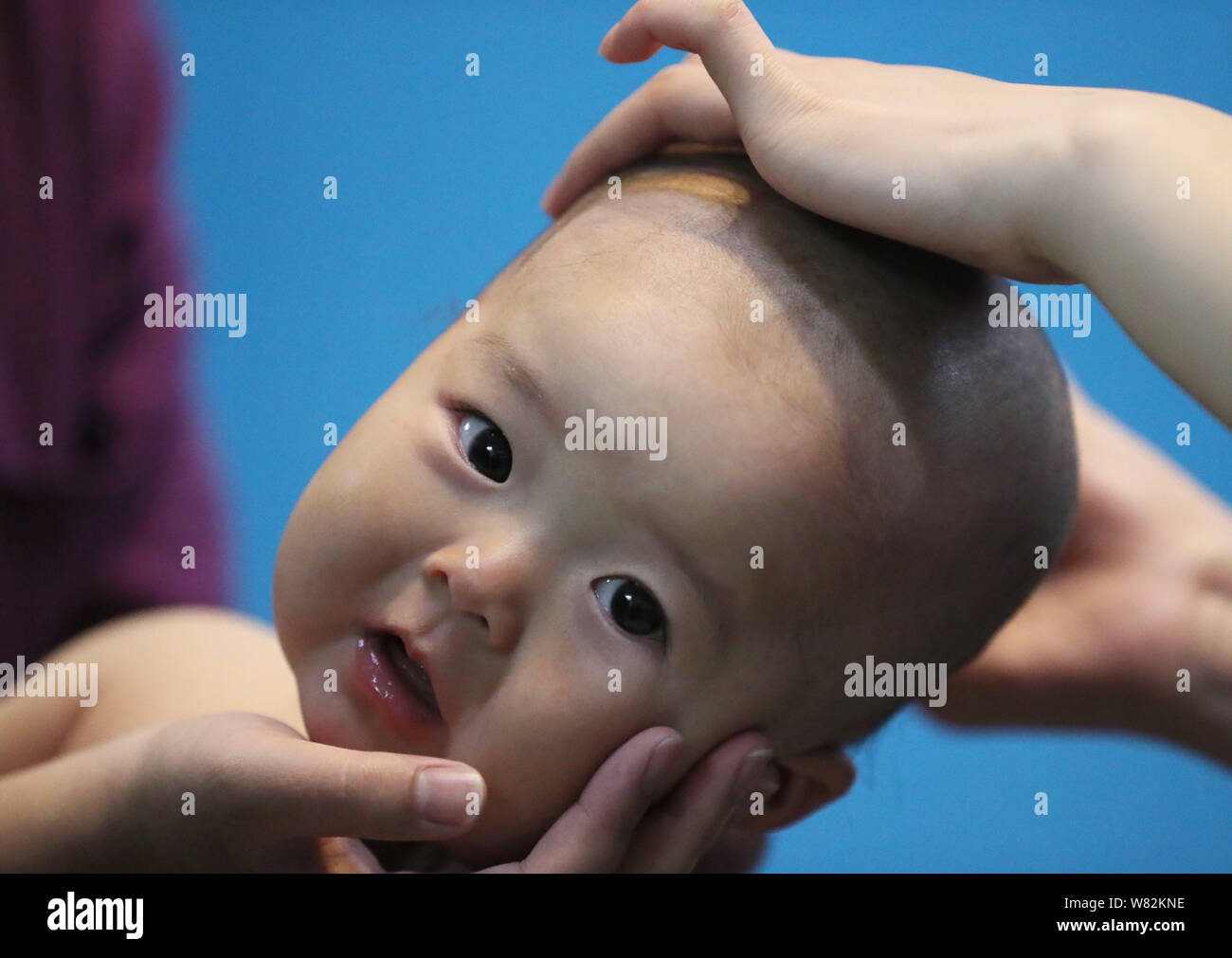 A Chinese baby has his hair cut to celebrate the Longtaitou Festival ...