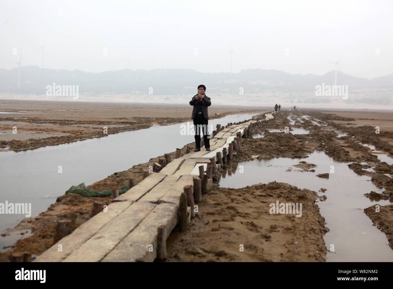 A tourist takes photos at the restored Qianyan Bridge at Poyang Lake in ...