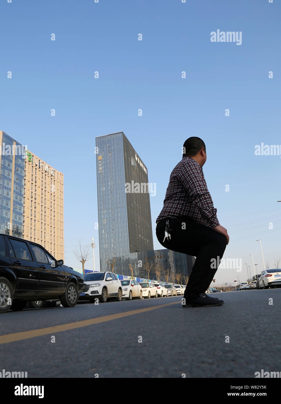 A pedestrian tries to "sit" on a chair-shaped building in Zhengzhou ...