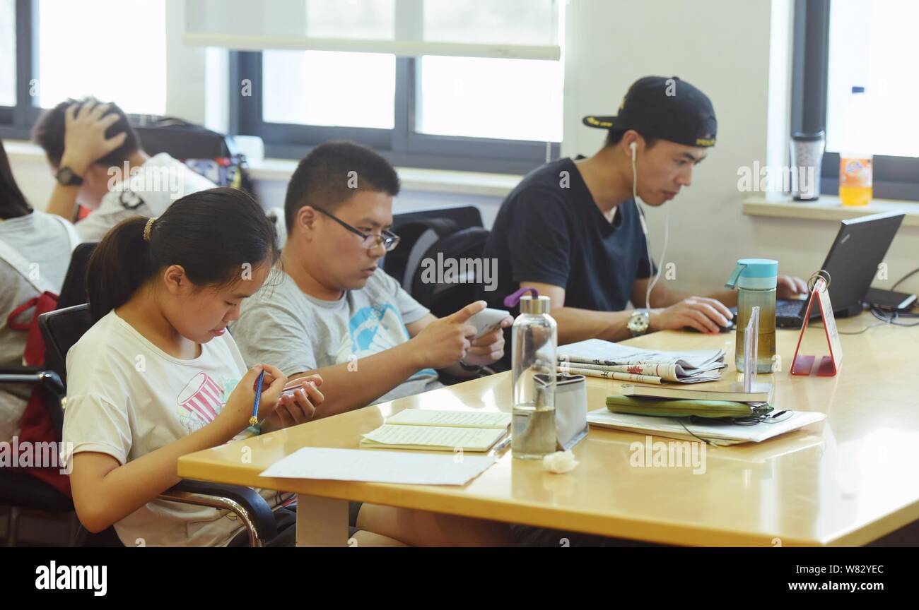 --FILE-Chinese people use their smartphones and laptop computer to surf ...