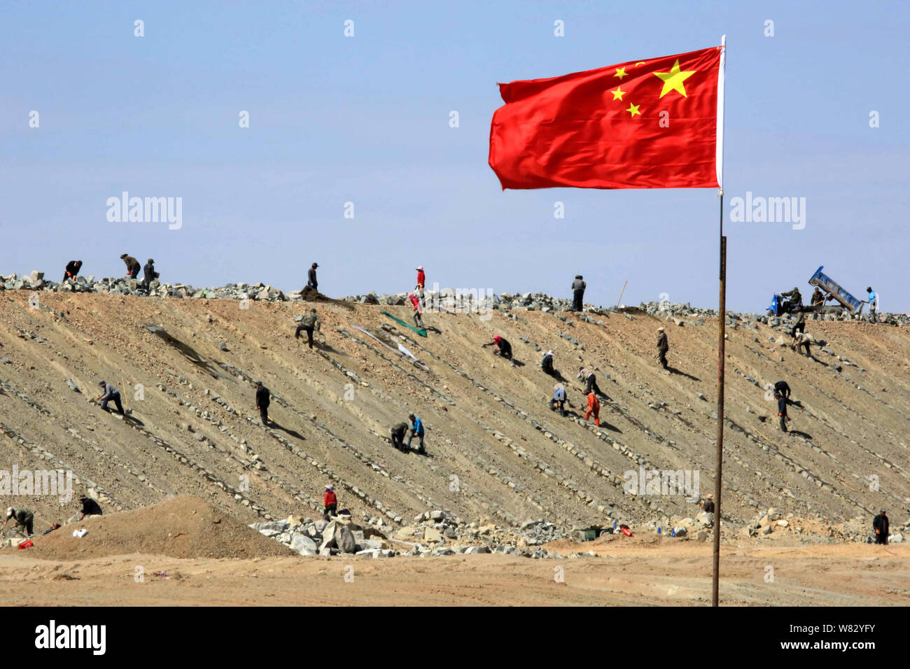 --FILE--A Chinese national flag flutters near a group of workers ...