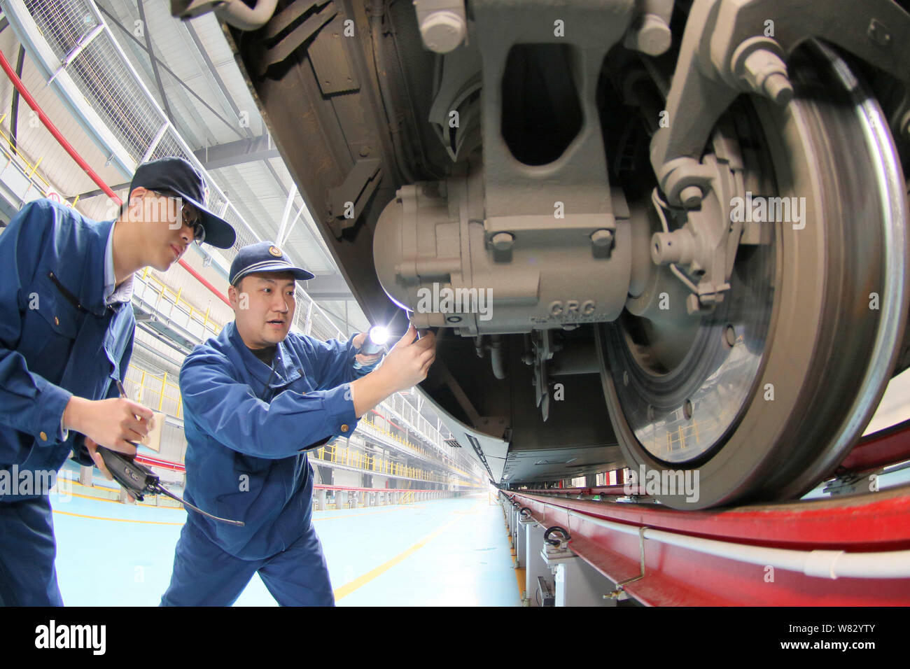 Chinese mechanics check a CRH (China Railway High-speed) bullet train ...