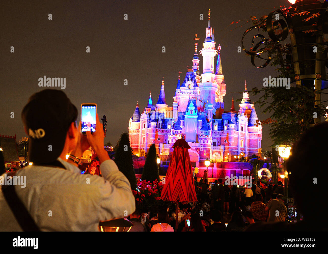 --FILE--A visitor takes photos of the illuminated Disney Castle in the ...