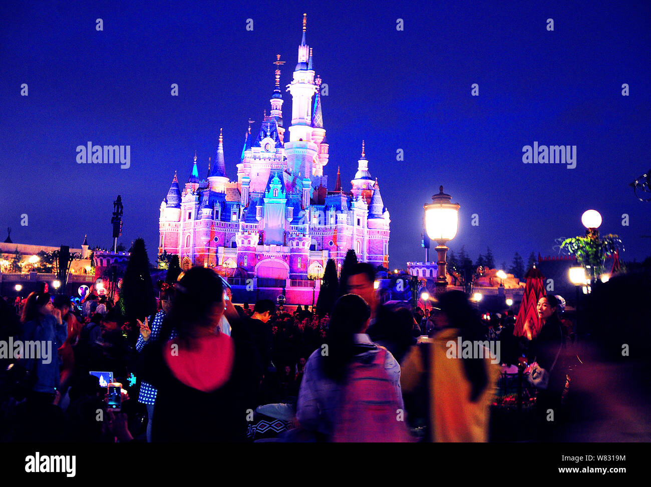 --FILE--Visitors look at the illuminated Disney Castle in the Shanghai ...