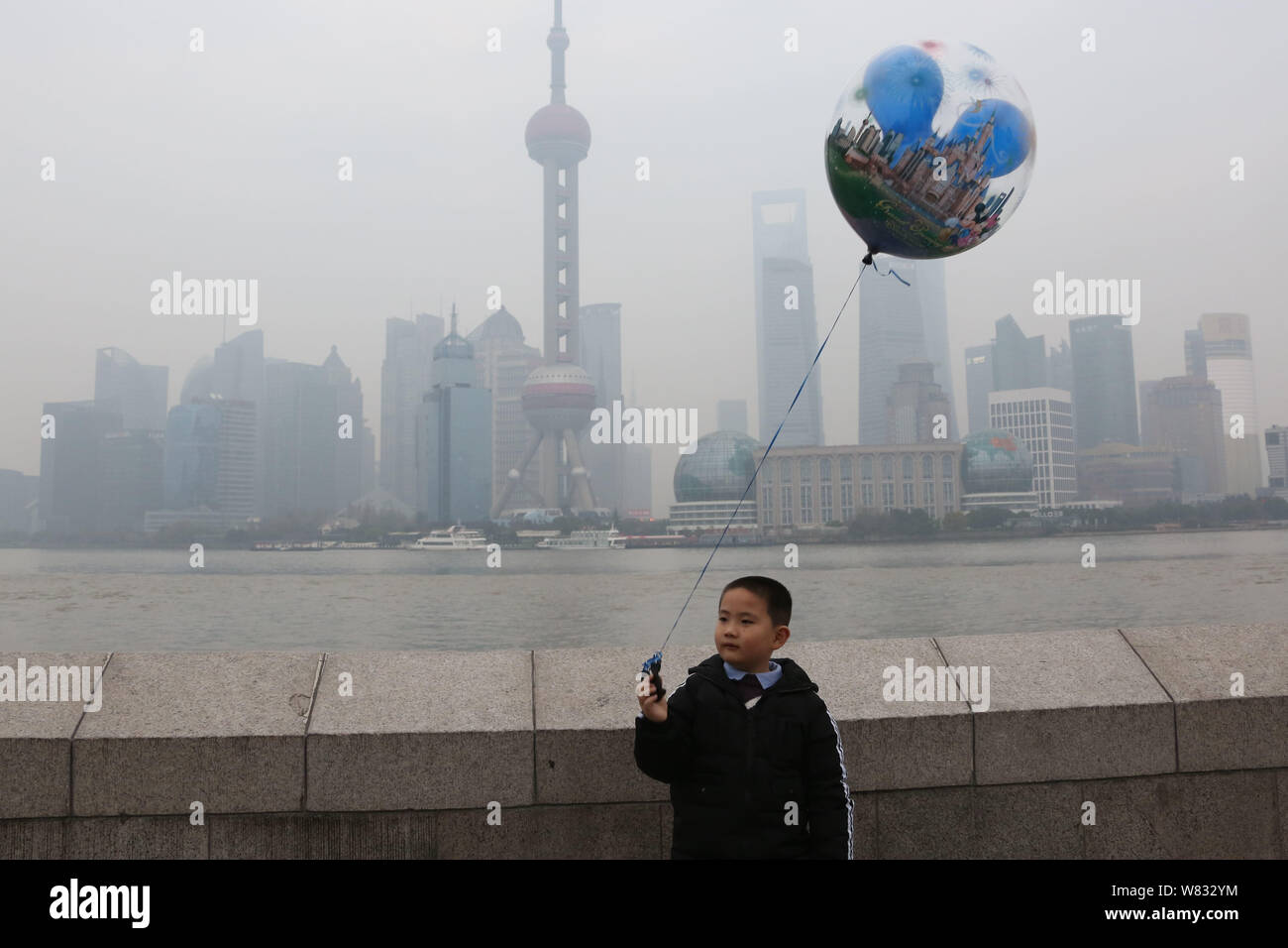 A young Chinese boy carries a balloon on the Bund in heavy smog in ...