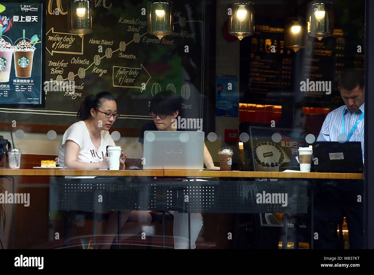 --FILE--Customers enjoy coffee and use their laptop computers at a cafe ...