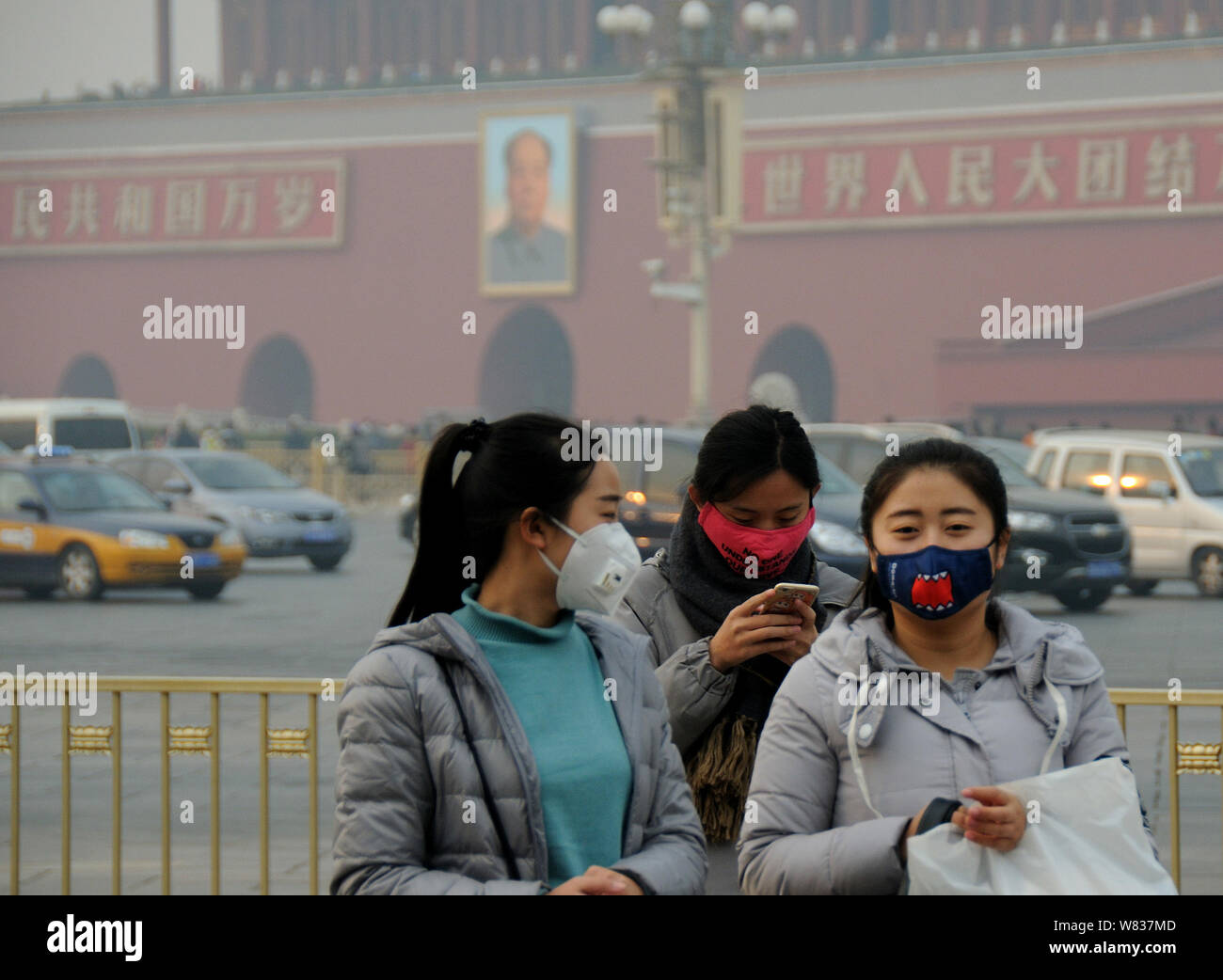 Tourists wearing face masks against air pollution visit the Tiananmen ...
