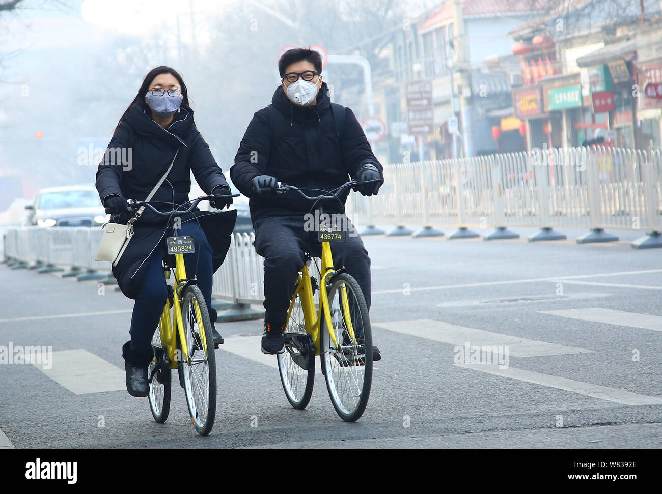 Cyclists wearing face masks against air pollution ride on the road in ...