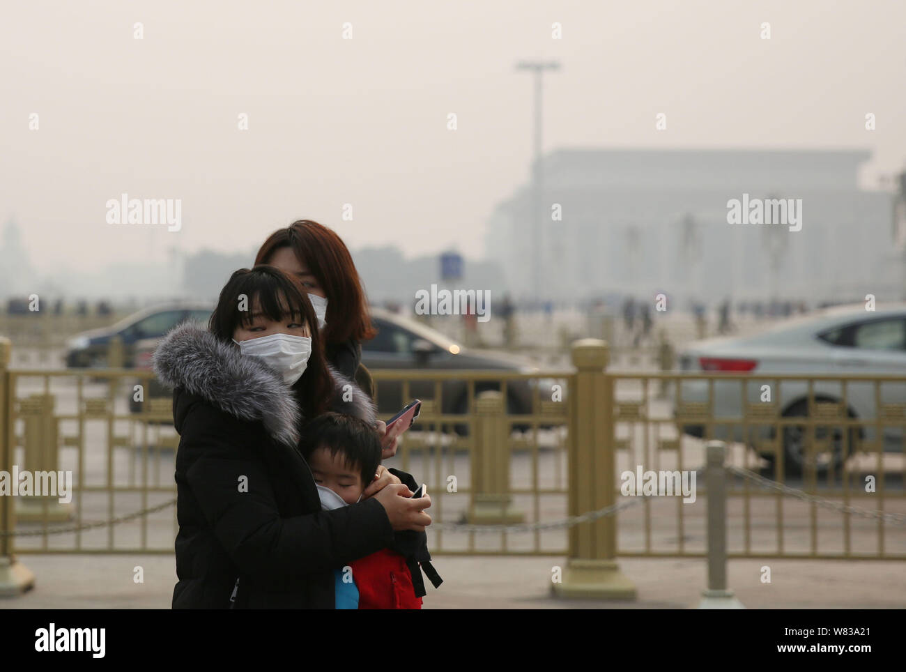 Pedestrians wearing face masks against air pollution walk past the ...