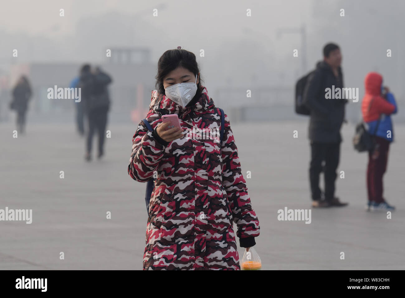 A pedestrian wearing a face mask against air pollution walks on the ...