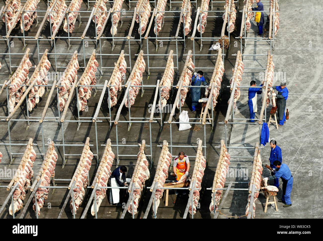 Chinese workers hang Jinhua hams to dry them in the sun in a factory of ...
