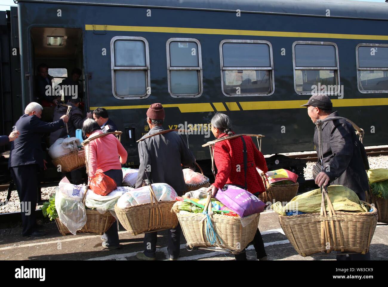Chinese farmers carrying baskets of vegetables queue up to board a ...