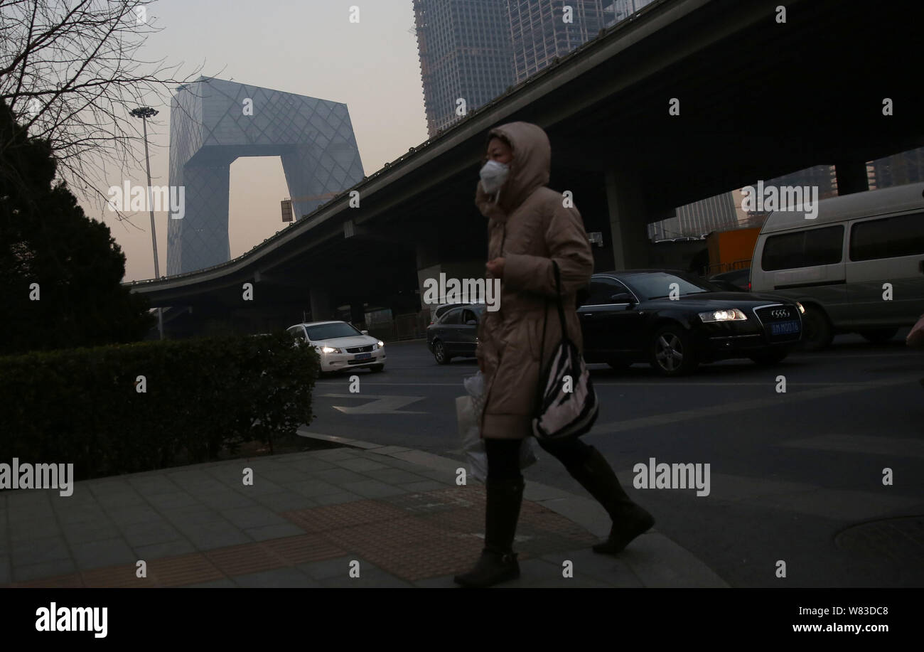 --FILE--A pedestrian wearing a face mask walks past the CCTV Tower ...